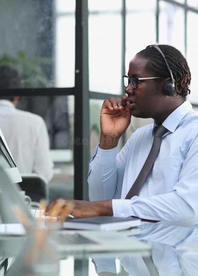 A Man at a Computer in a Call Center Talking Using Headphones with a ...