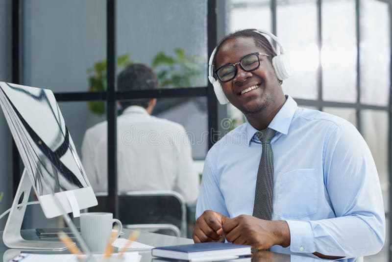 A Man at a Workplace at a Table in Front of a Computer with Headphones ...