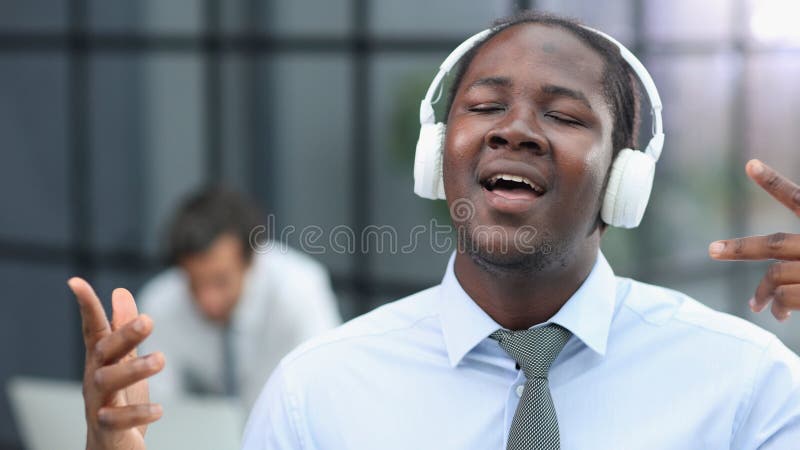A Man at a Workplace at a Table in Front of a Computer with Headphones ...