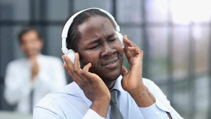 A Man at a Workplace at a Table in Front of a Computer with Headphones ...