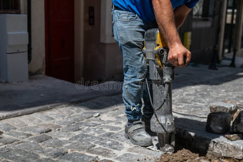 A Man Works with an Air Hammer at a Road Construction Site. the Worker ...