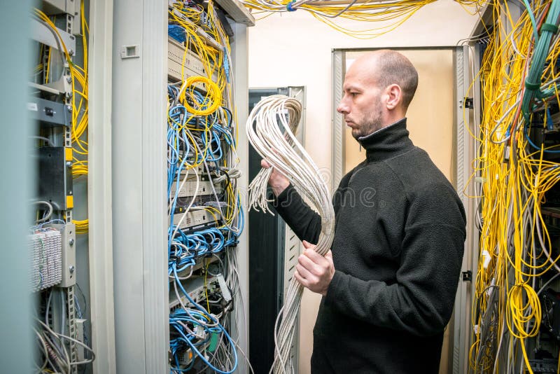 A Man Works with Communication Cables in a Data Center. the Signalman ...