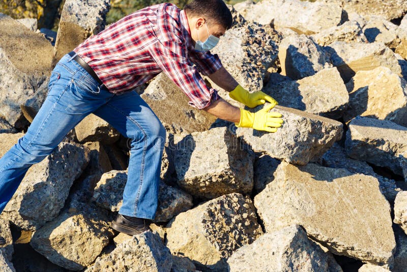 A Man Works with a Pile of Stones and Broken Pieces of Concrete ...