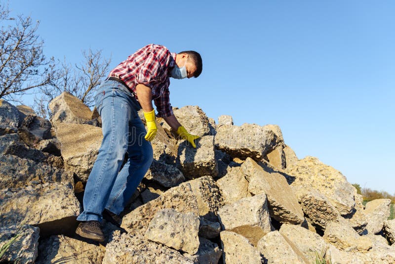 A Man Works with a Pile of Stones and Broken Pieces of Concrete ...