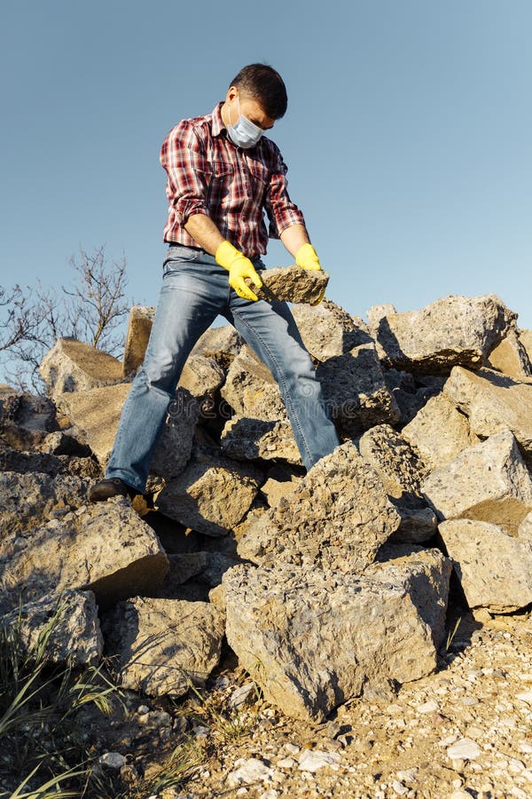 A Man Works with a Pile of Stones and Broken Pieces of Concrete ...