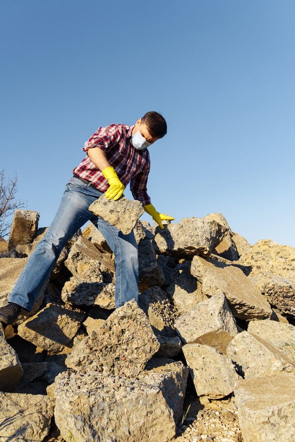 A Man Works with a Pile of Stones and Broken Pieces of Concrete ...