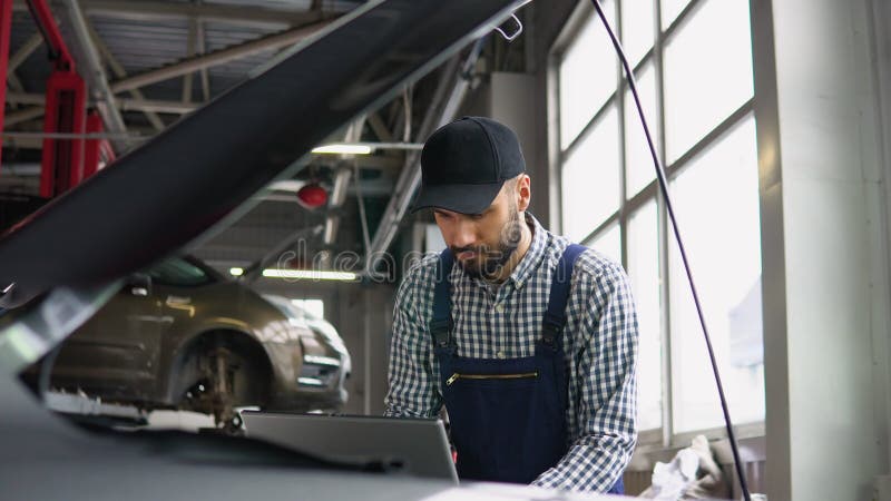 Man at the Workshop in Uniform Using Laptop for His Job for Fixing ... Man at the Workshop in Uniform Using Laptop for His Job for Fixing ...