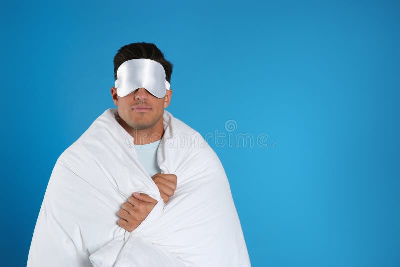 Man Wrapped in Blanket Wearing Sleeping Mask on Blue Background. Space ...