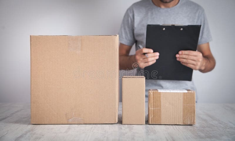 Man Writing in Clipboard. Cardboard Boxes on the Desk Stock Image ...