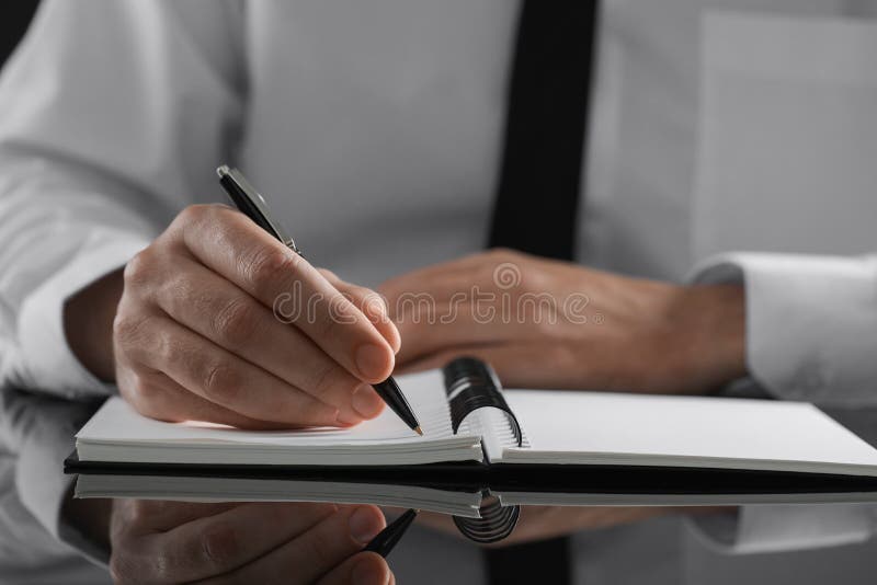 Man Writing in Notebook at Black Table, Closeup. Space for Text Stock ...