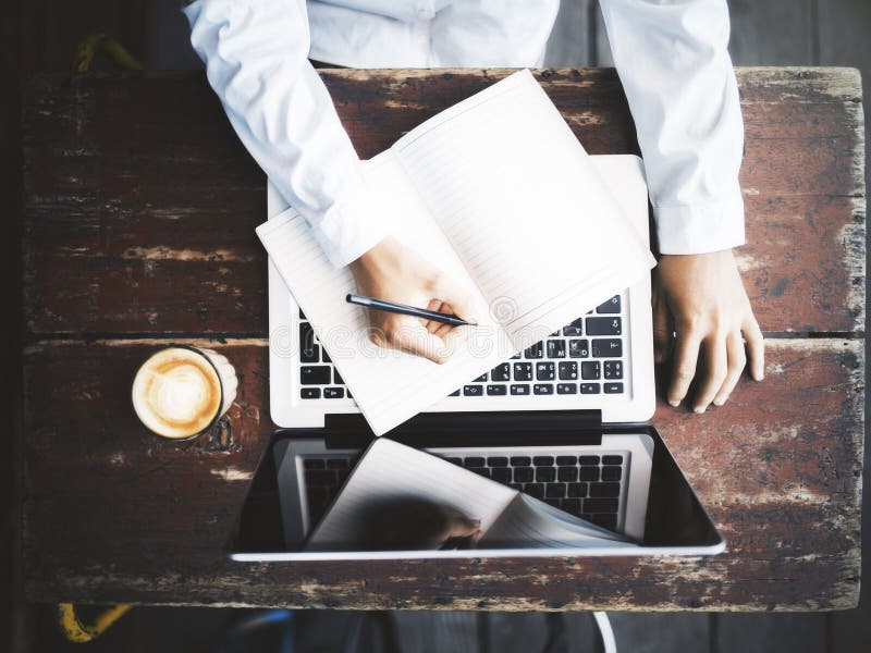 Man Writing in Notepad with Laptop and Coffee Mug on Wooden Table Stock ...
