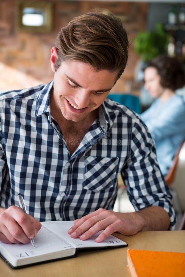 Man Writing Notes in Diary in Coffee Shop Stock Image - Image of people ...