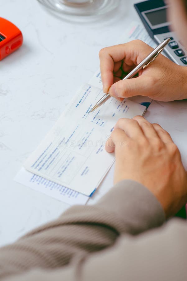 Man Writing a Payment Check at the Table with Calculator and Stamp ...