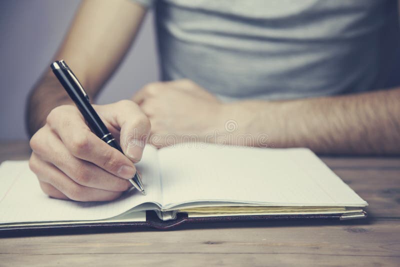 Man Writing on Wooden Table Stock Image - Image of male, diary: 108005261