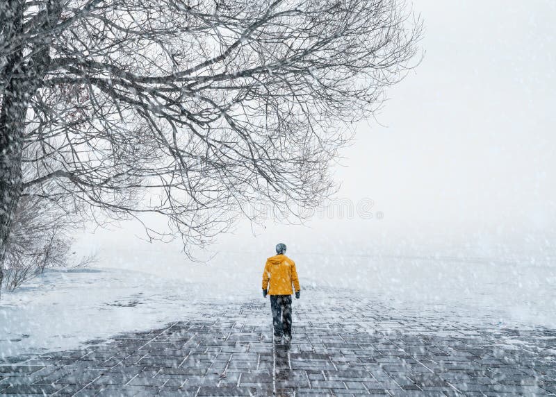 A Man in a Yellow Coat Walking on the Snow-covered Road. Stock Image ...