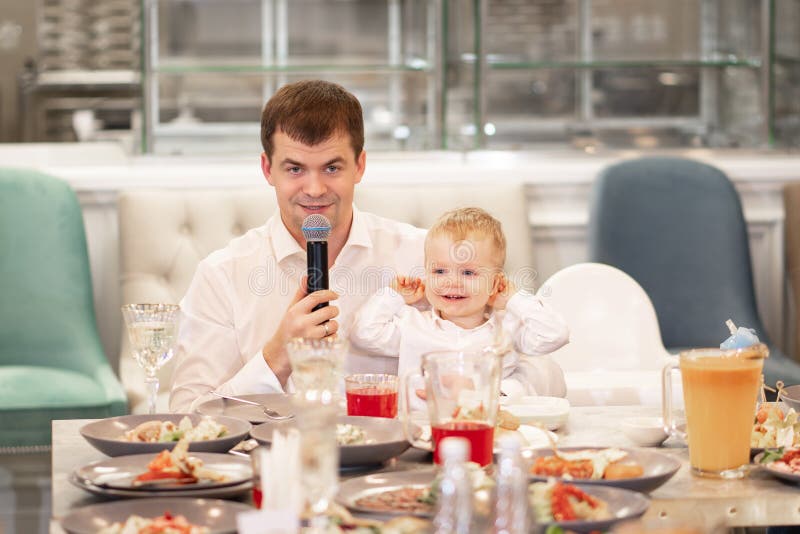 A Man with a Young Son Sits at a Table and Makes a Toast into the ...