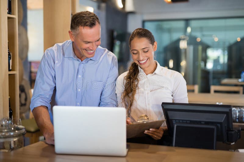 Manager and Bartender Discussing Over Clipboard in Bar Stock Image ...
