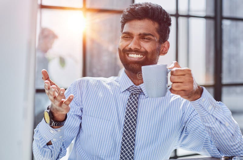 A Handsome Young Man is Sitting by the Window in the Office, Drinking ...