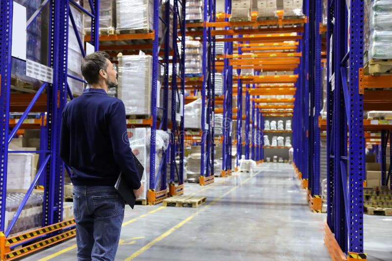 Manager Holding Clipboard in Warehouse with Lots of Products, Back View ...