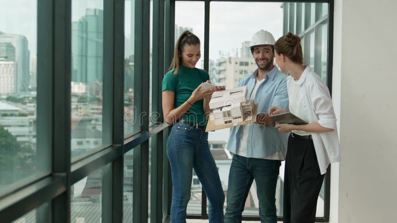 Manager Holds House Model while Team Discuss about House Design ... Manager Holds House Model while Team Discuss about House Design ...