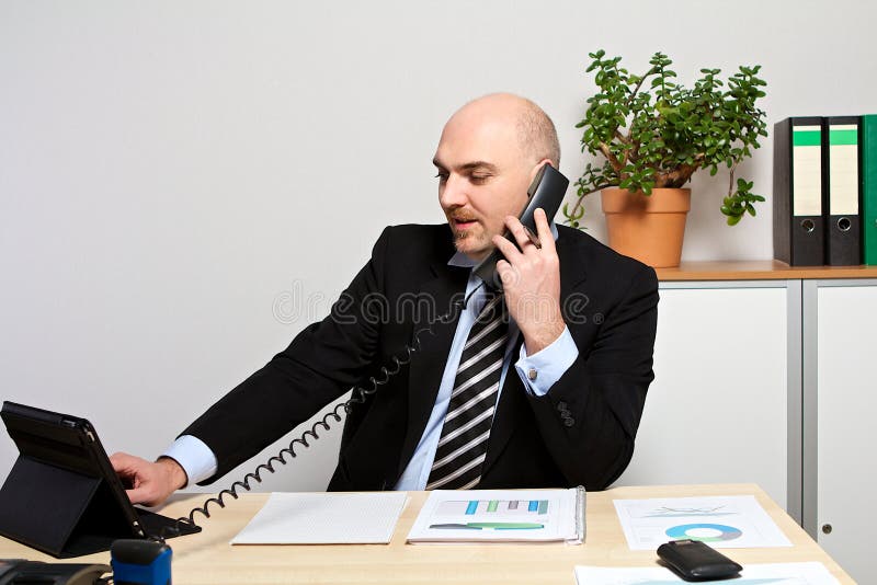 Manager on the Phone while he Compares Data on the Tablet Stock Photo ...