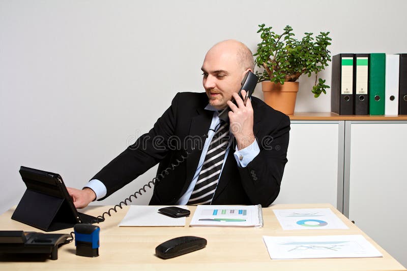 Manager on the Phone while he Compares Data on the Tablet Stock Photo ...