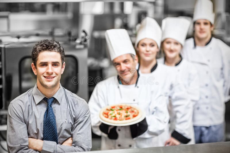 Manager Standing in Front of Chefs Holding Pizza in Kitchen Stock Photo ...