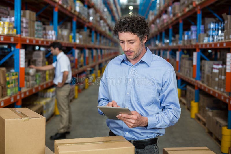 Manager Working on a Tablet in the Middle of Cardboard Boxes Stock ...