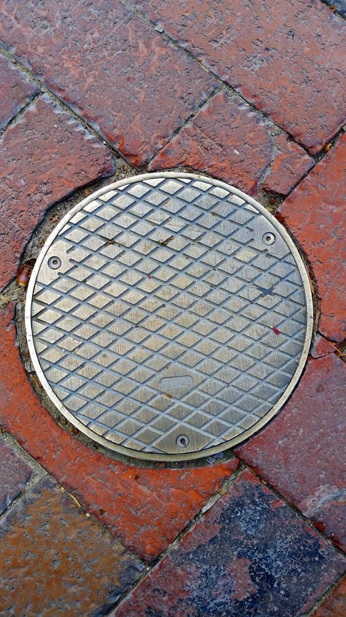 Manhole Cover on a Brick Road Stock Photo - Image of cast, cobblestone ...