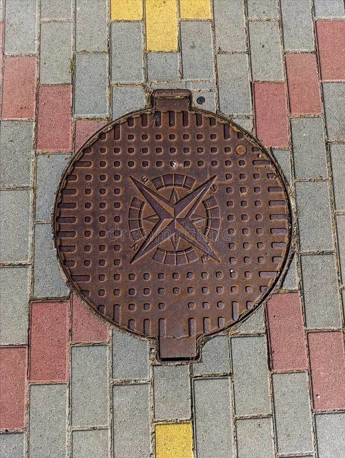 A Manhole Cover on a Sidewalk with a Compass on it Stock Image - Image ...