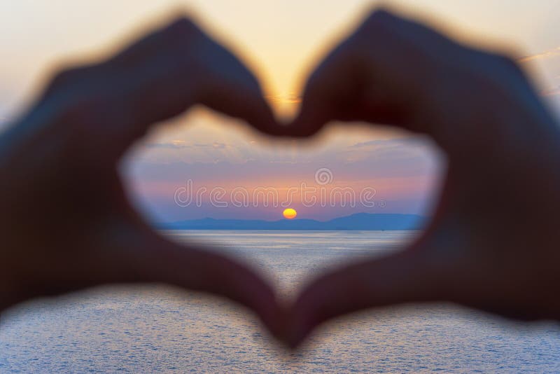 Mani Che Formano Una Forma Del Cuore Con Il Tramonto Immagine Stock ...