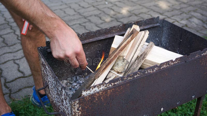 A Mans Hand is Using Matches To Start a Fire in a Grill for Barbeque ...