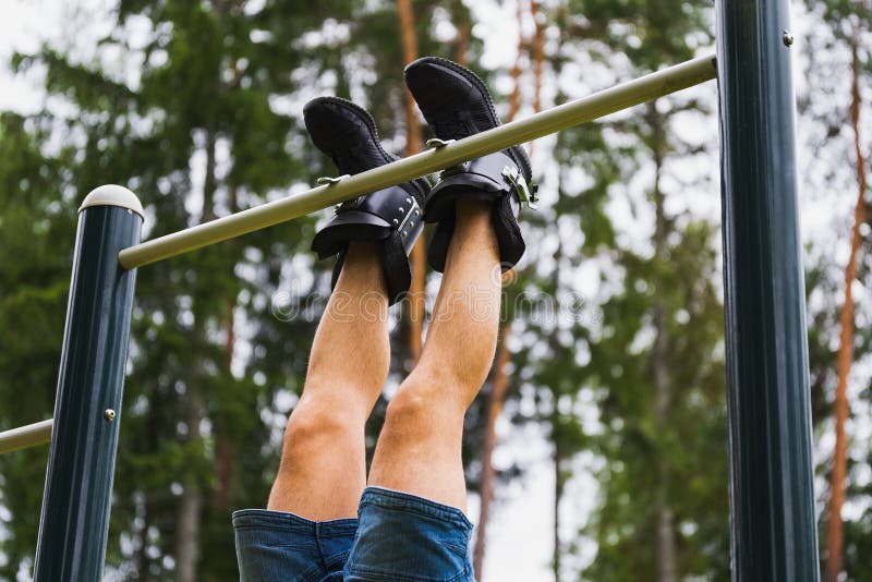 A Mans Legs in Gravity Boots Hangs on a Horizontal Bar Outdoors on a ...