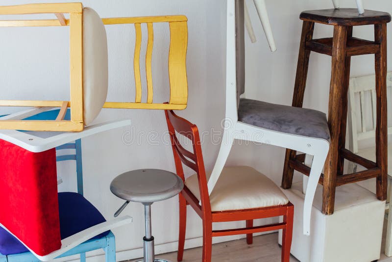 Many Different Chairs of Different Colors Stand at the White Wall Stock ...