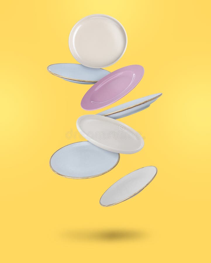 Many Different Plates Falling on Yellow Background Stock Photo - Image ...