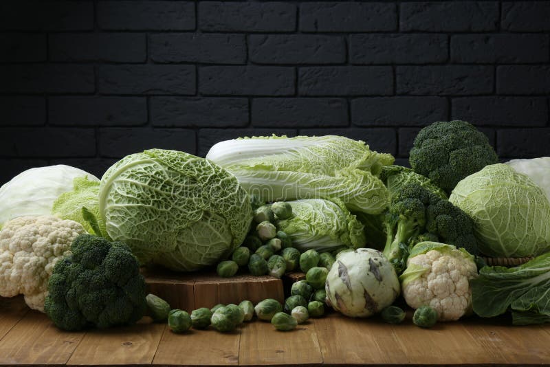 Many Different Types of Fresh Cabbage on Wooden Table Near Brick Wall ...
