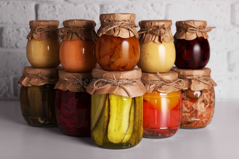 Many Glass Jars with Different Preserved Products on Light Grey Table ...