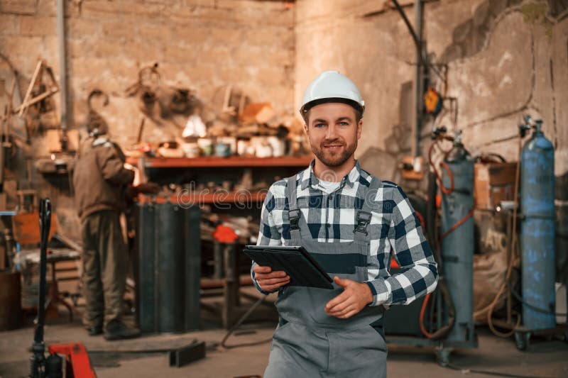 Many Objects Behind. Factory Male Worker in Uniform is Indoors Stock ...