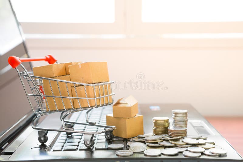 Many Parcel Boxes in a Shopping Cart and Coins Stack on Laptop Computer ...