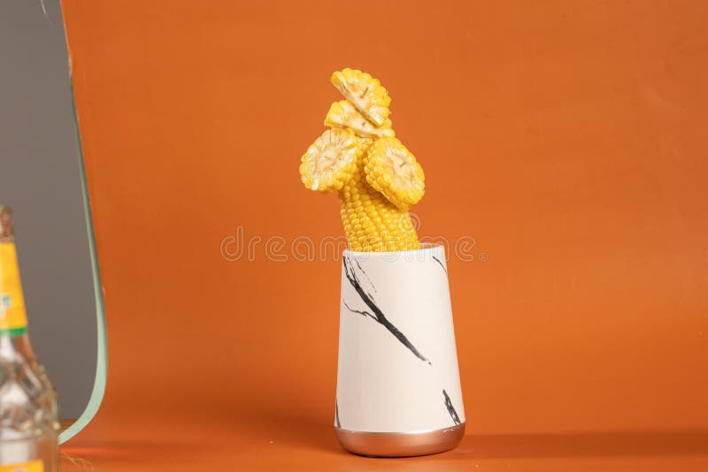 Marble Vase with a Corn on the Cob and Sliced Corn Pieces on an Orange ...