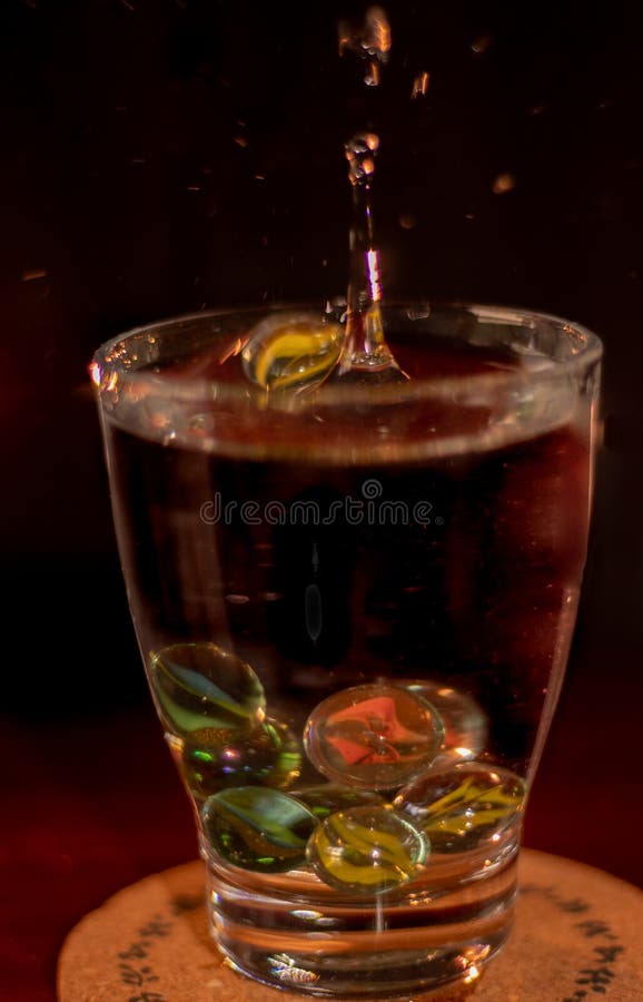 Marbles Falling into a Glass of Water Stock Photo - Image of dripped ...