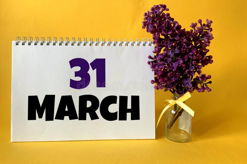 March 31 on a White Notebook on a Yellow Background.Next To it is a ...