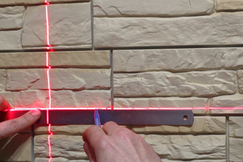 Marking a Wall Using a Laser Level. Red Beam on a Stone Wall. Repair ...