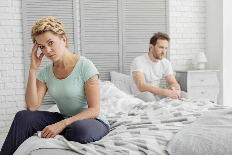 Couple Sitting On Different Sides Of Bed Not Talking After Argument