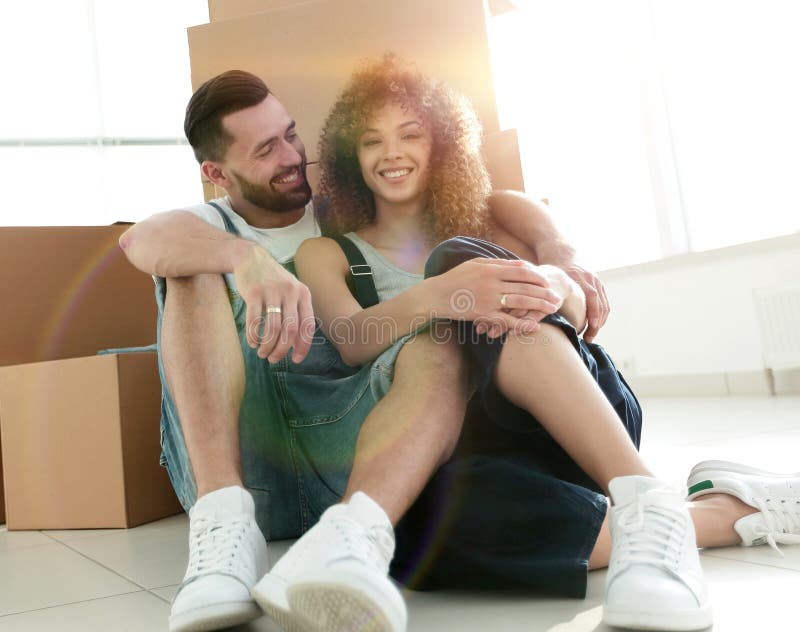 Married Couple Sitting Near Cardboard Boxes In A New Apartment Stock