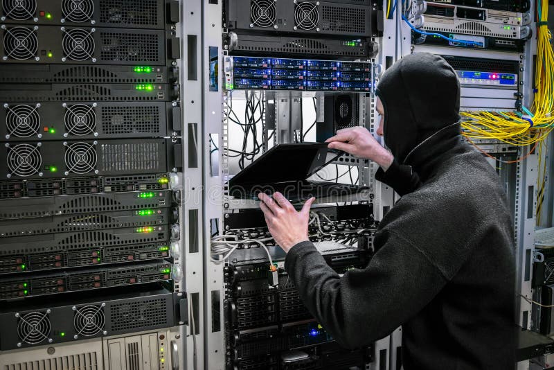 A Masked Thug Closes a Laptop in a Server Room. Hacker Breaks into a ...