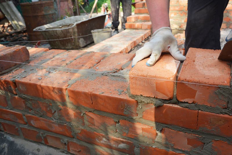 Mason is Laying Bricks Applying Mortar To Build a Brick Wall of the ...