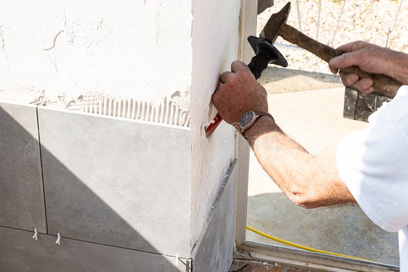 The Mason Prepares the Wall with a Chisel before Laying a Ceramic Tile ...