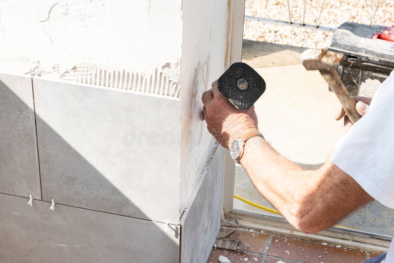 The Mason Prepares the Wall with a Chisel before Laying a Ceramic Tile ...