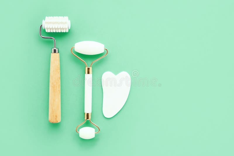 Massage Rollers and Gua Sha Massager for the Face on Green Background ...